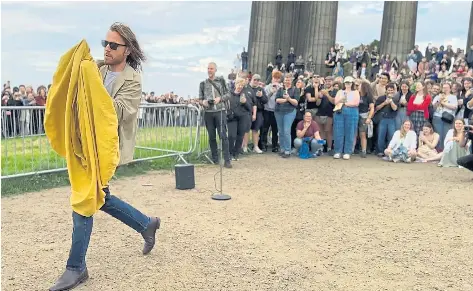 Hundreds gather on Calton Hill to watch a man folding a bed sheet ...