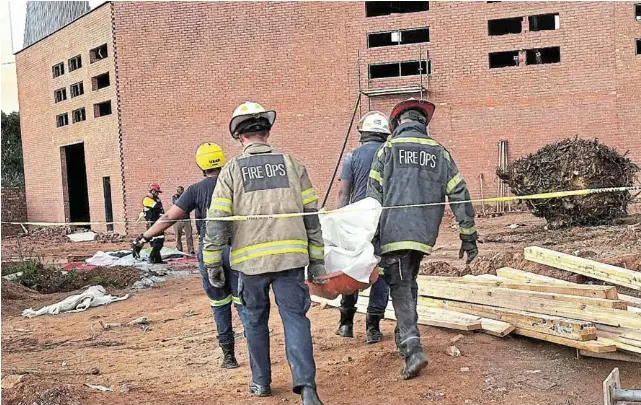 Rescue workers remove a body from the rubble where six other people ...